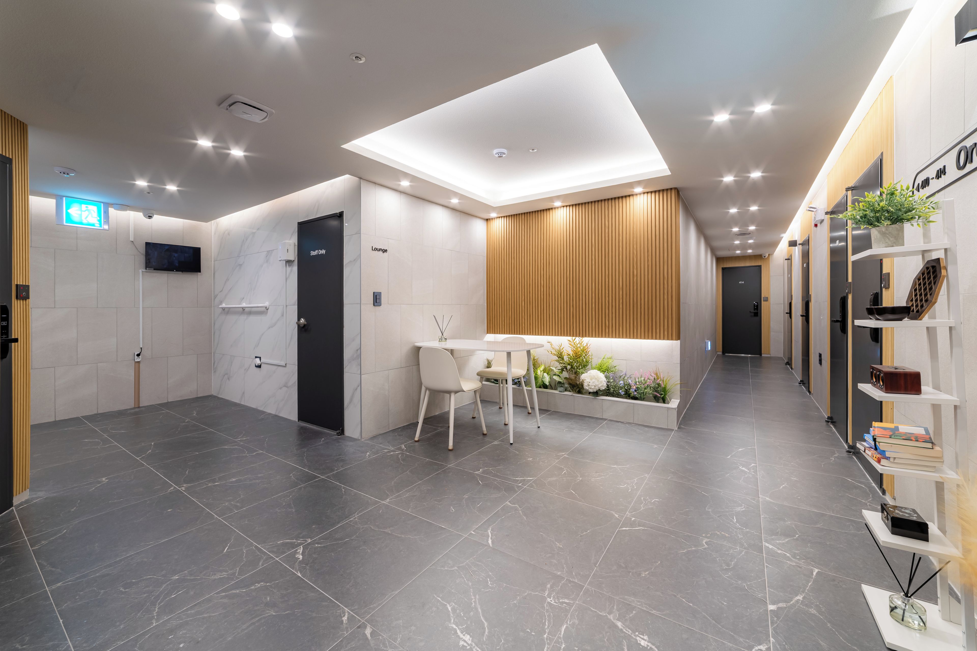 Um saguão moderno de hotel com área de estar, balcão de recepção e espaço para refeições.