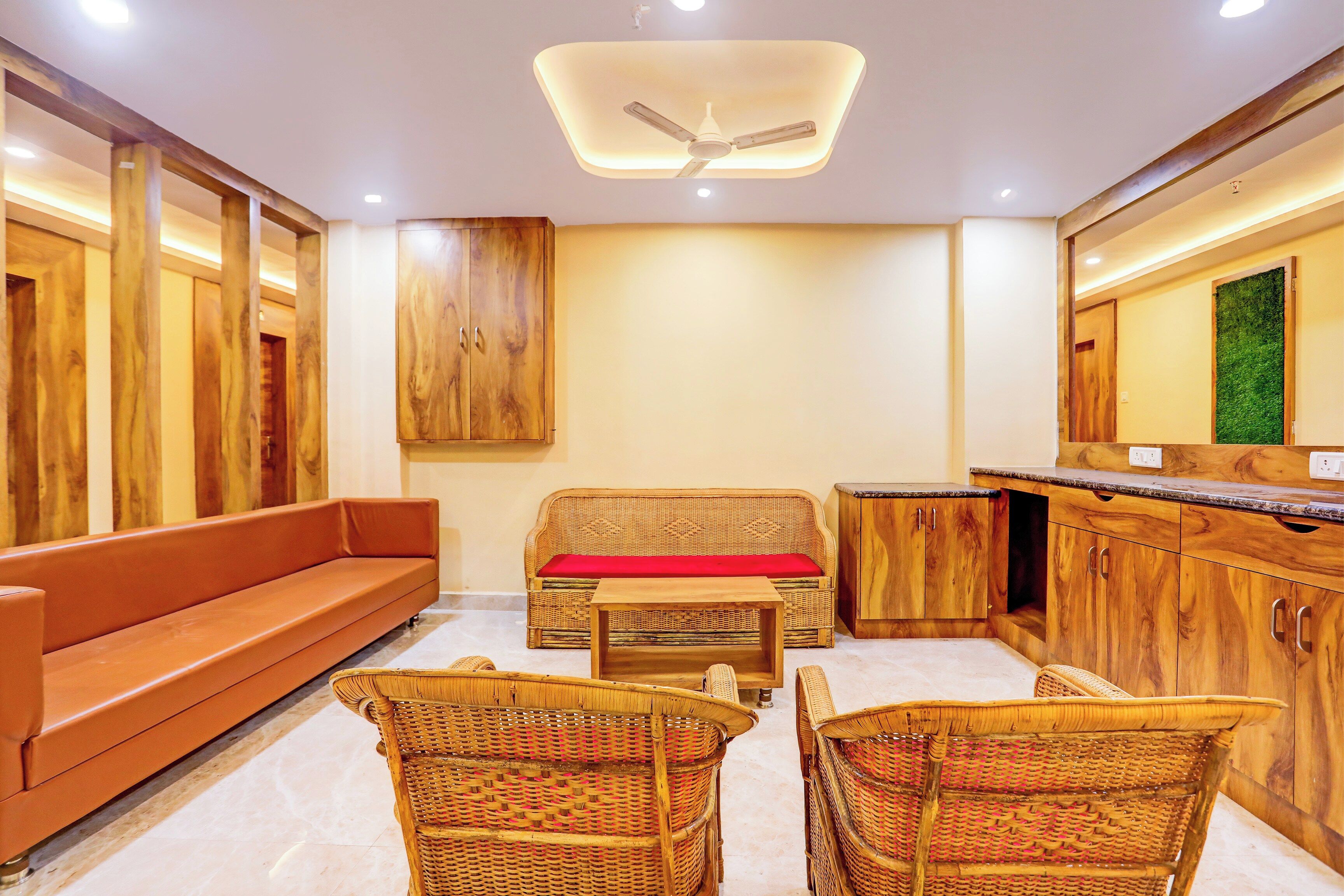 Quarto com sofá de madeira, cadeiras de vime, uma mesa pequena e um ventilador de teto.