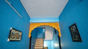 Um corredor com paredes azuis, escada de madeira e um arco decorativo.