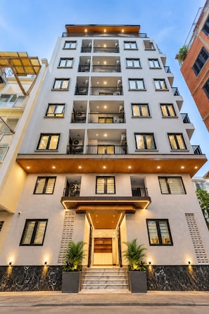 Um hotel com vários andares, fachada moderna, varandas e entrada central com degraus.