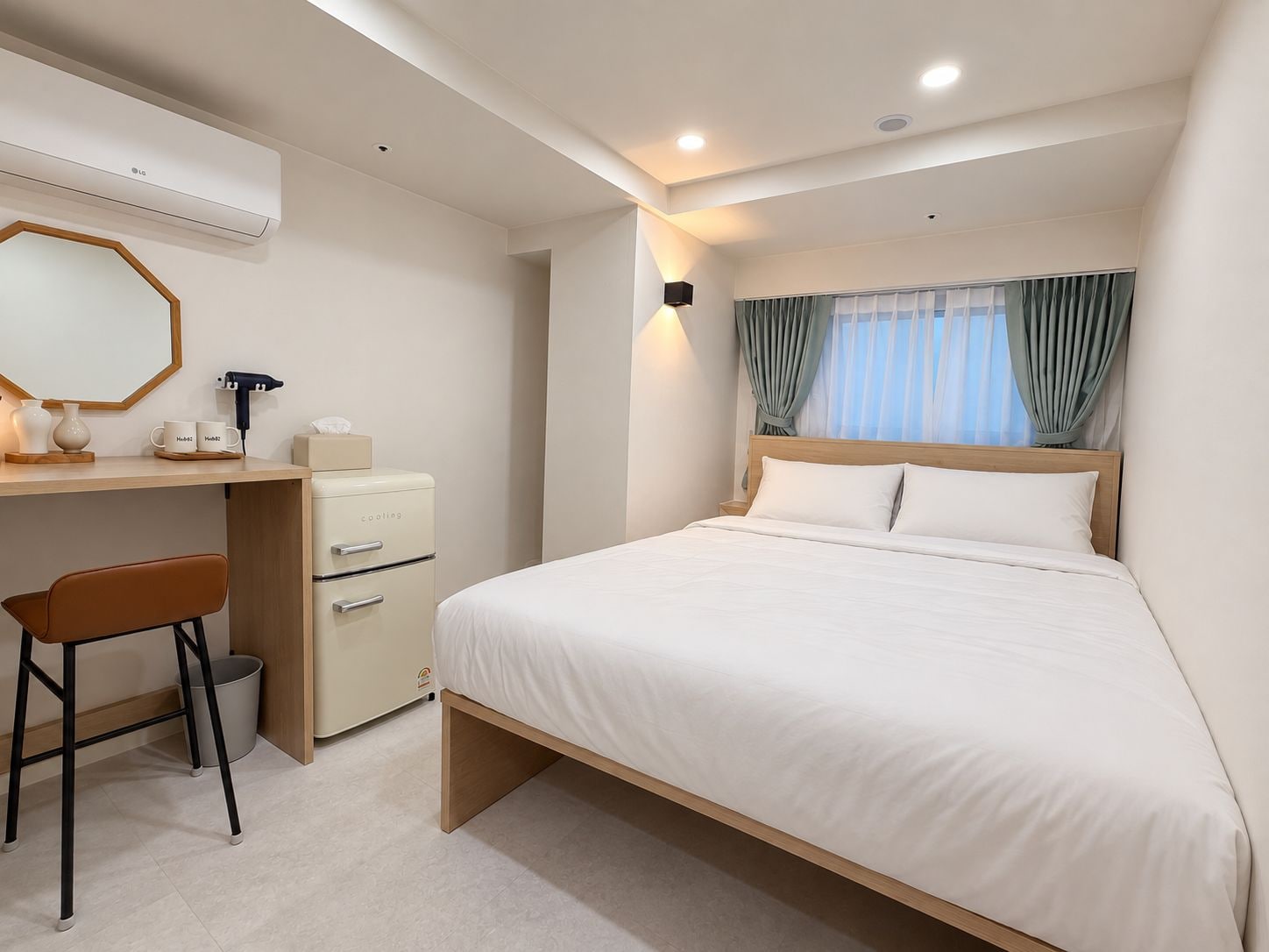 Quarto de hotel com cama, escrivaninha com cadeira, armário e janela com cortinas.