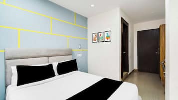 Quarto de hotel com uma cama, uma parede com padrões geométricos e uma porta.