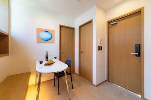 Quarto de hotel com área de refeições, um quadro na parede e uma porta com fechadura.