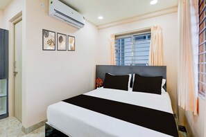 Quarto com cama, ar condicionado, janela com cortinas e decoração nas paredes.