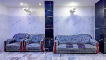 Quarto com dois sofás de couro, piso com padrão marmorizado e parede em tom escuro.