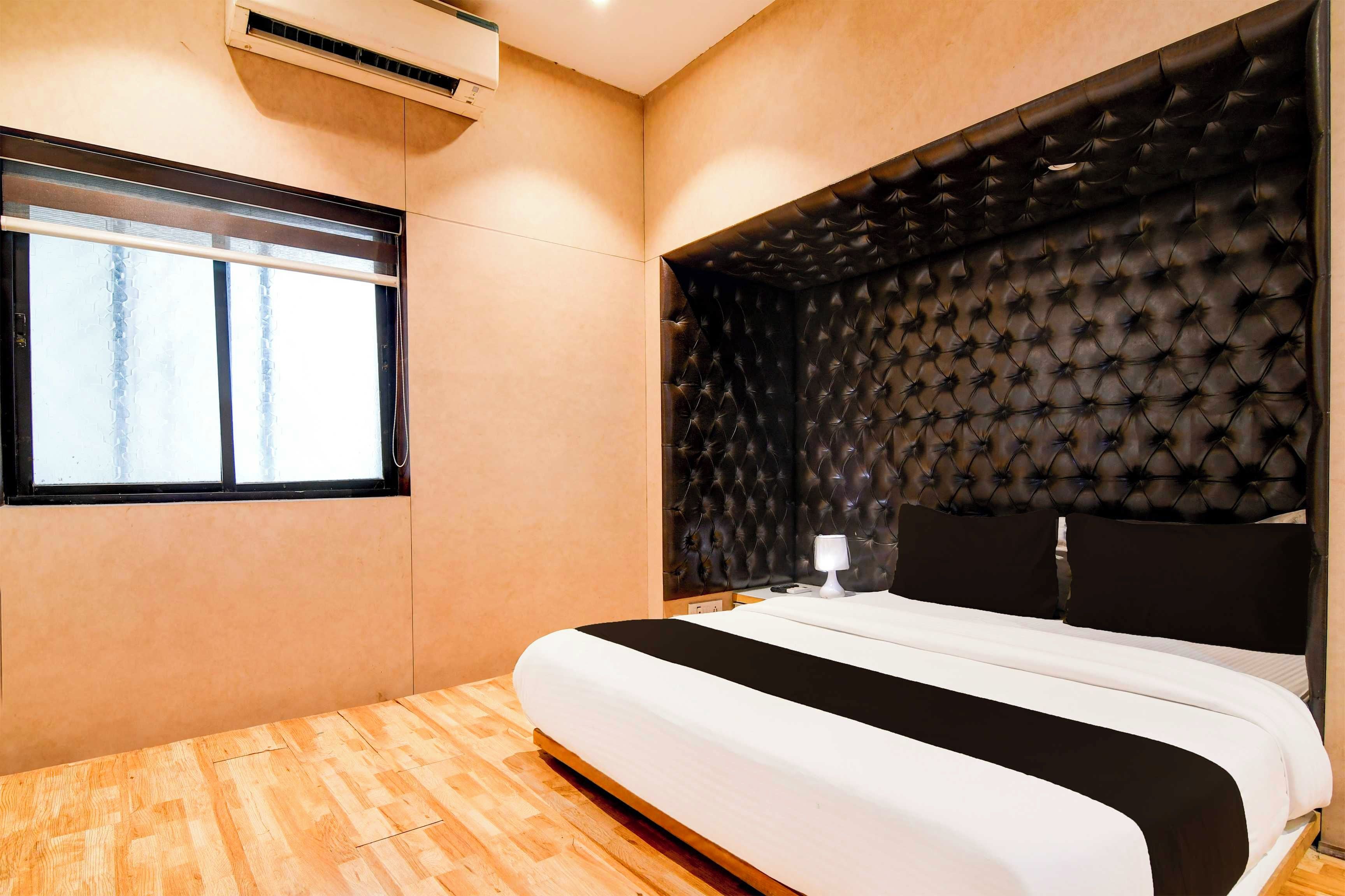 Um quarto moderno com uma cama grande, uma janela e um ar condicionado fixado na parede.