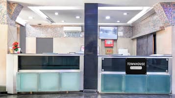 Uma área de recepção com um visor digital, uma placa indicando que é uma townhouse de serviço e uma câmera de segurança.