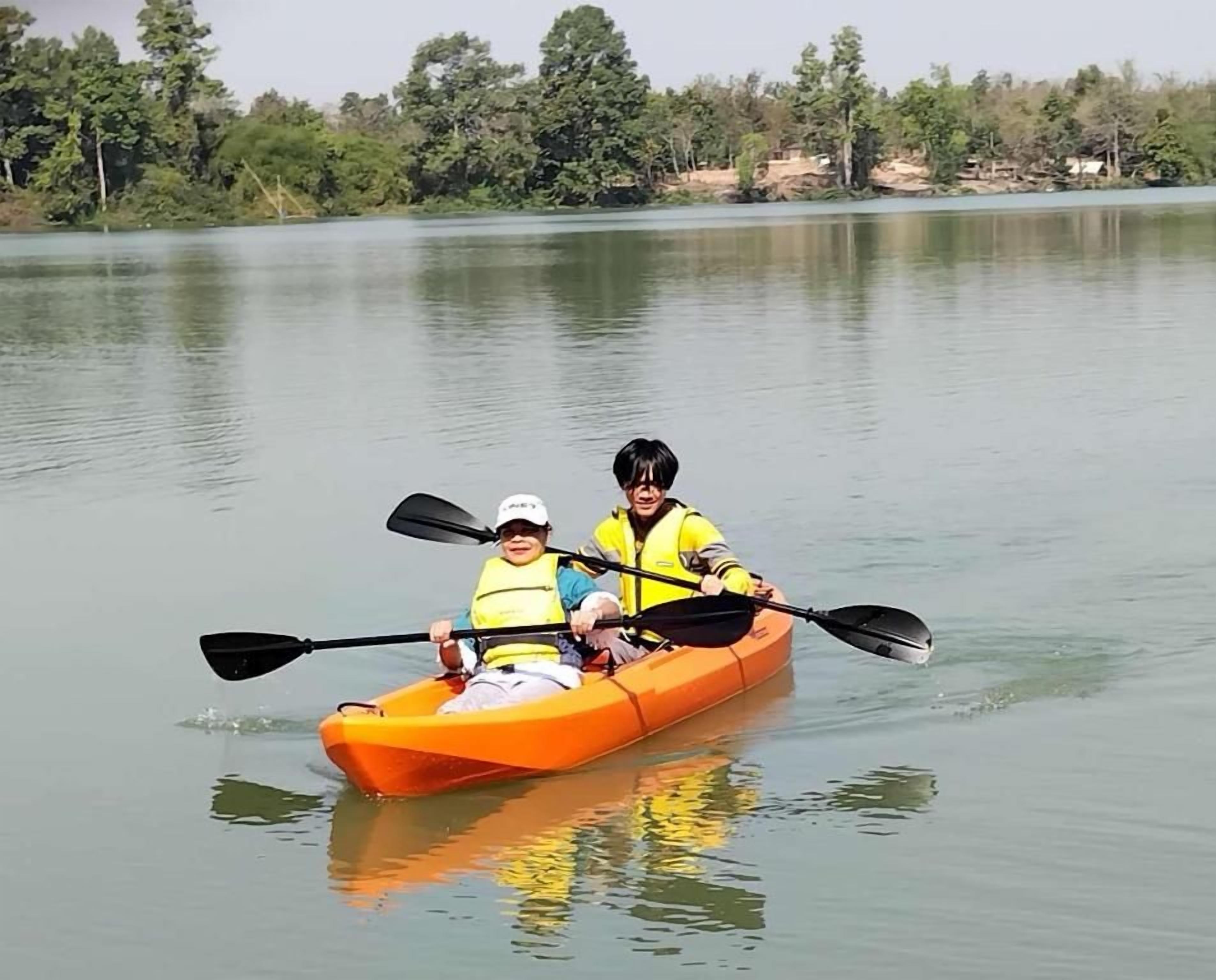 Duas pessoas em um caiaque em um lago calmo, cercado por árvores.