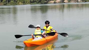 Duas pessoas em um caiaque em um lago calmo, cercado por árvores.