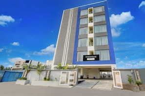 Uma casa geminada moderna com entrada destacada, placa visível indicando serviço OYO e céu azul claro ao fundo.