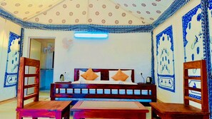 Quarto com cama, duas cadeiras, uma mesa e paredes estampadas.