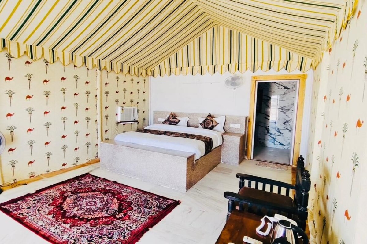 Quarto com cama, ventoinha, espelho e tapete estampado.
