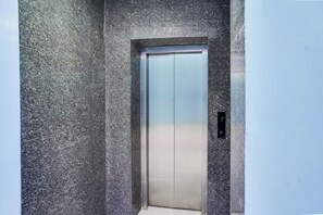 Um elevador com interior metálico e painel de controle com visor verde.