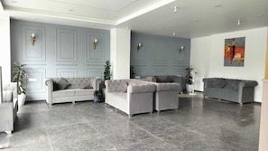Uma sala de estar ampla com sofás cinza, uma mesa de centro e arandelas decorativas.