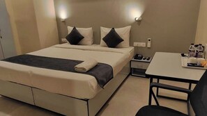 Quarto de hotel com cama, mesa de cabeceira, cadeira e uma mesinha com bandeja.