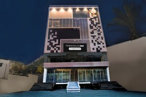Um edifício de vários andares com uma placa chamativa 'TOWNHOUSE OAK', uma escadaria que leva à entrada e uma área de piscina na frente.