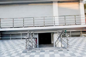 Um edifício com vários andares, persianas fechadas, piso xadrez e grades de metal.