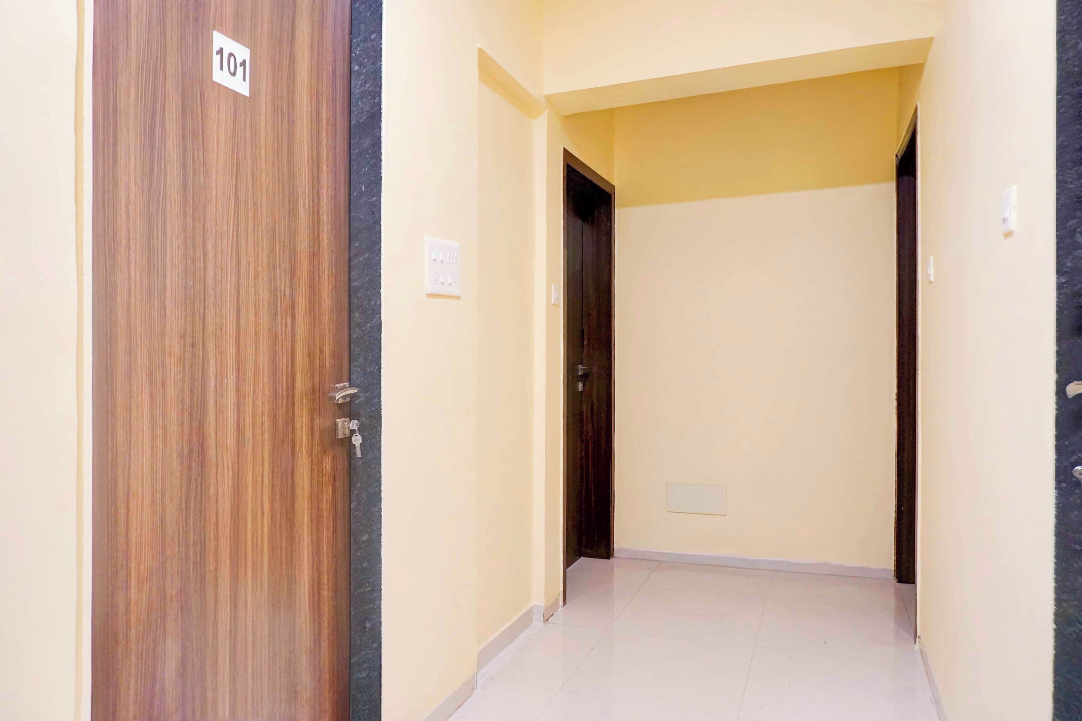 Corredor com porta de madeira identificada com o número '101' e um interruptor de luz na parede.