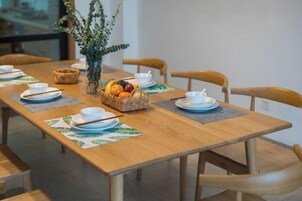 Mesa de jantar posta com pratos, tigelas e uma cesta de frutas.
