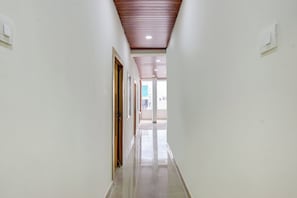 Um corredor com teto de madeira, paredes brancas e chão de azulejos.