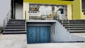Um edifício com escadaria que leva a uma varanda, portas duplas com padrão de pavão e fachada cinza e amarela.