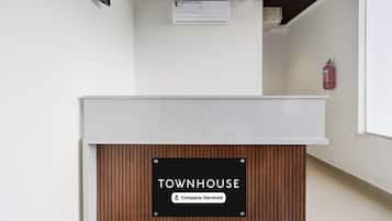 Uma mesa de recepção com uma placa que diz 'TOWNHOUSE Company Serviced'.