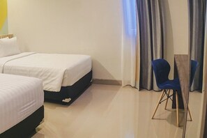 Quarto de hotel com duas camas, uma escrivaninha e uma cadeira.