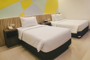 Quarto de hotel com duas camas, uma mesa de cabeceira com telefone e parede com padrão geométrico.