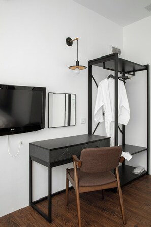 Quarto moderno com beliche, escrivaninha com televisão de tela plana, cadeira e luminária pendente.