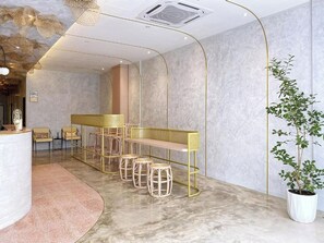 Interior moderno com balcão de recepção, área de estar e planta em vaso.