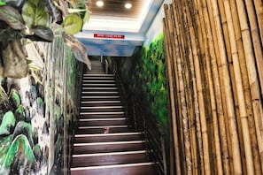Uma escadaria com um painel de bambu de um lado e um muro com folhagem verde do outro.