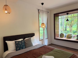 Quarto com cama, janela com cortinas e luminárias pendentes.