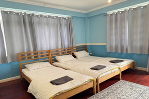 Quarto com duas camas de solteiro, cabeceira de madeira e tapete estampado.