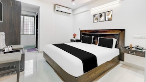 Quarto de hotel moderno com uma cama grande, ventoinha no teto, ar condicionado, mesa de cabeceira com telefone e janela com vista.
