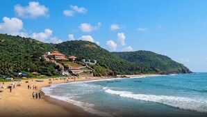 Uma praia com casas numa encosta, areal e o oceano.