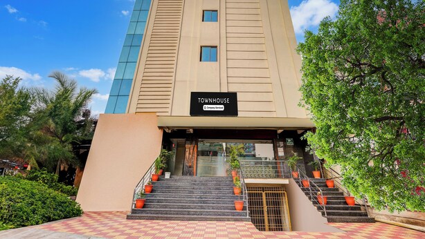 Um edifício de vários andares com uma placa que diz 'TOWNHOUSE Company-Serviced'.