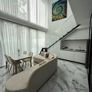 Interior moderno com área de jantar, sofá, escada e cozinha.