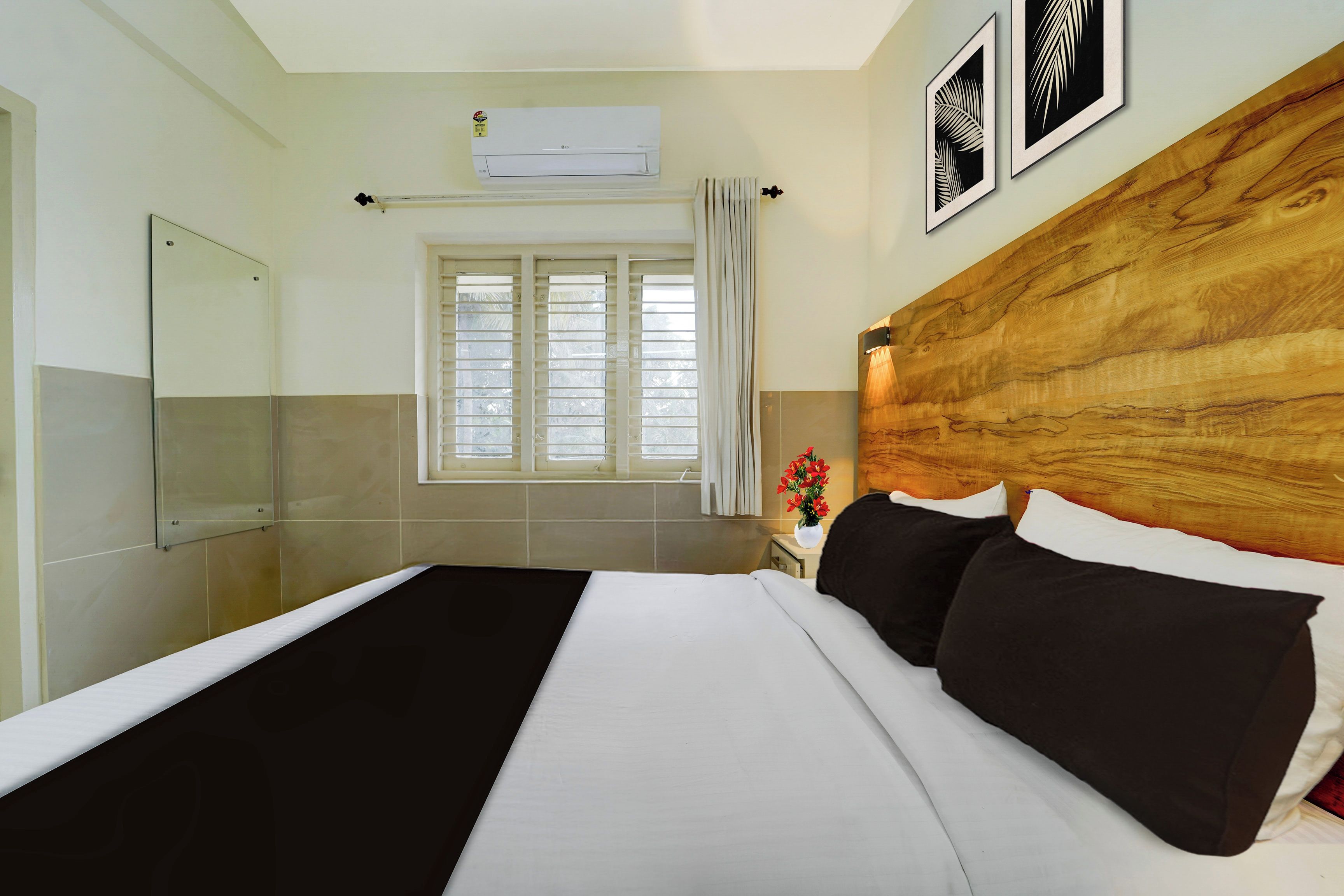 Quarto de hotel com uma cama grande, cabeceira de madeira, janela com cortinas, ar condicionado fixado na parede e um quadro emoldurado na parede.