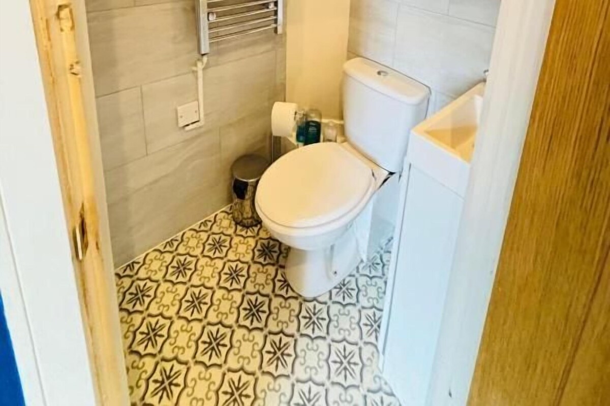 Um banheiro com vaso sanitário, chuveiro e piso revestido de azulejos.