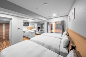 Quarto de hotel moderno com duas camas, cozinha compacta, banheiro e vista para o exterior.