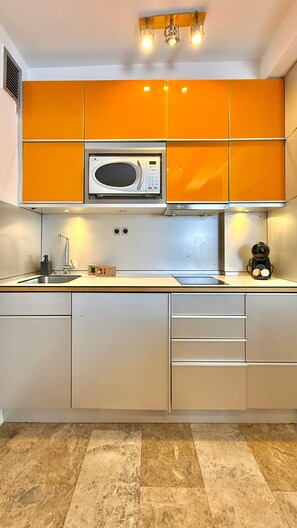 Cozinha equipada com micro-ondas, pia e armários.