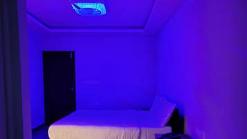 Quarto com cama, mesa de cabeceira e luminária no teto.