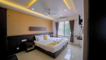 Quarto de hotel com cama, mesa de cabeceira e televisão.