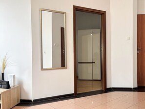 Um corredor com porta de madeira, um espelho e um armário de madeira com um vaso.