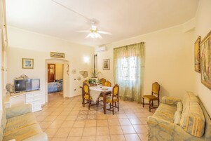 Uma sala de jantar com mesa, cadeiras e televisão.