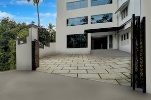 Um edifício moderno de dois andares com um caminho de entrada pavimentado e portão.