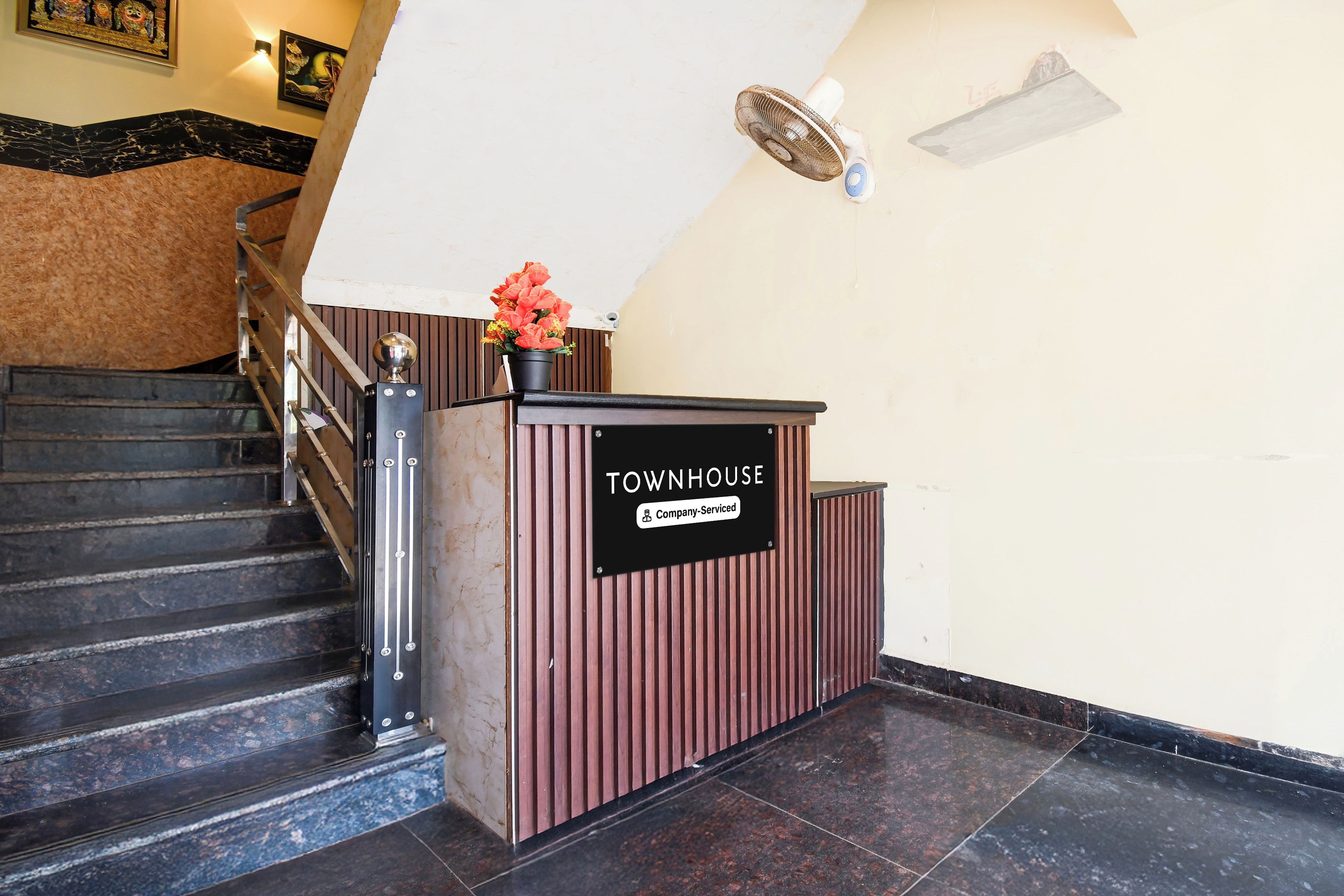 Balcão de recepção com uma placa indicando 'TOWNHOUSE' e escadas com corrimão.