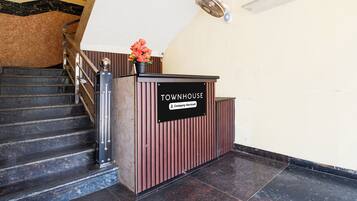 Balcão de recepção com uma placa indicando 'TOWNHOUSE' e escadas com corrimão.