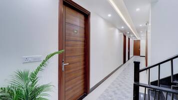 Corredor de hotel com portas de madeira, escada e planta em vaso.