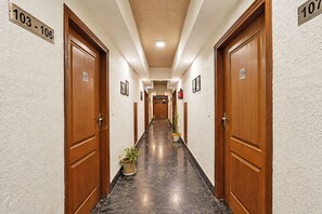 Corredor de hotel com portas de madeira numeradas de 103 a 106 e 110, dando acesso aos quartos.